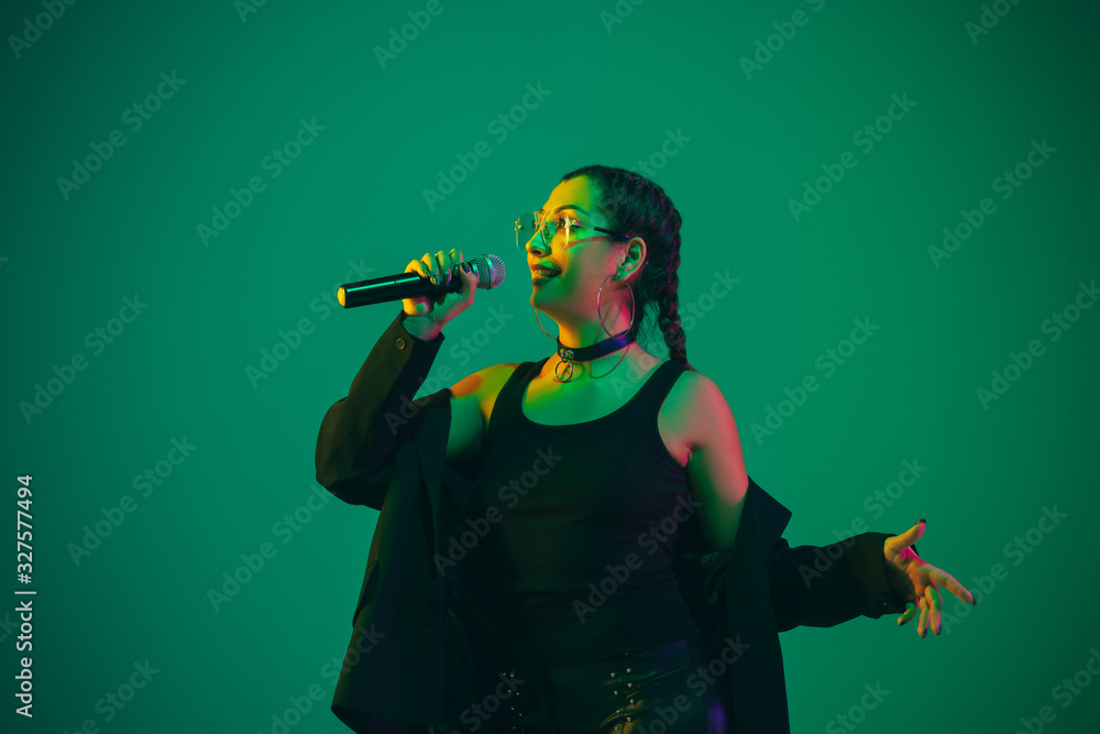 Caucasian female singer portrait isolated on green studio background in ...