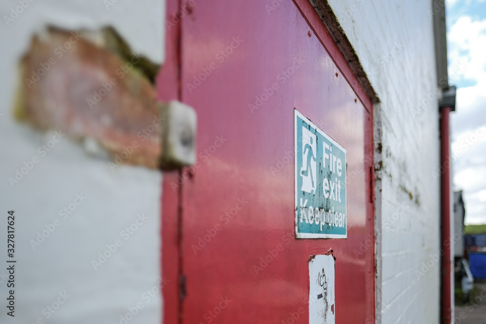 Shallow focus of an old Fire Exit and No Smoking sign seen attached for ...