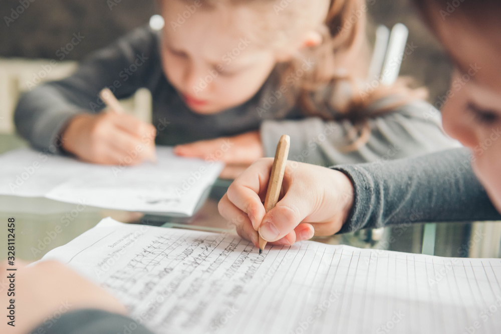 Schoolboy and schoolgirl writing letters. Close-up pencil in the hand ...
