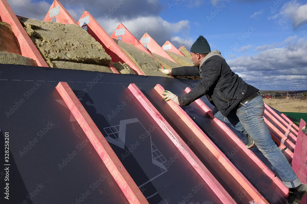 Insulation and waterproofing of the roof surface, the worker nails the ...