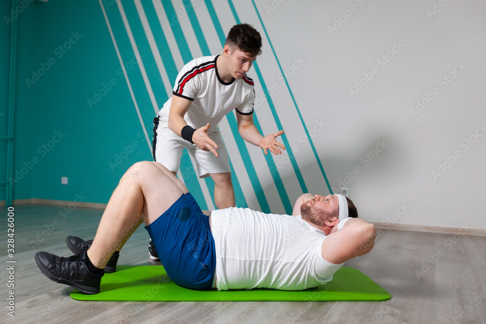 Fat man looks exhausted while doing exercises on abdominal muscles ...
