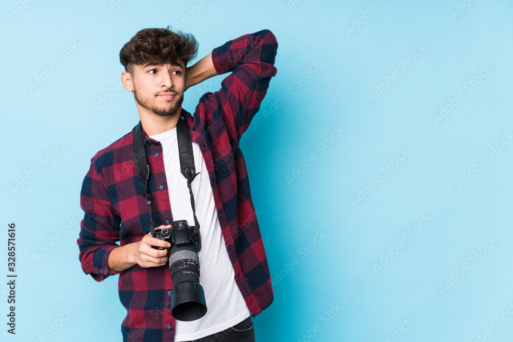 Young arab photographer man isolated touching back of head, thinking ...