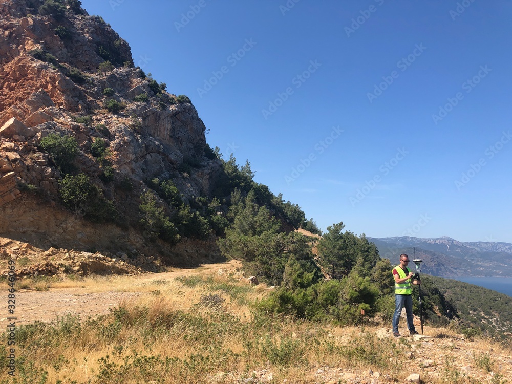 Geodetic engineer surveyor in white hard hat doing measurements with ...
