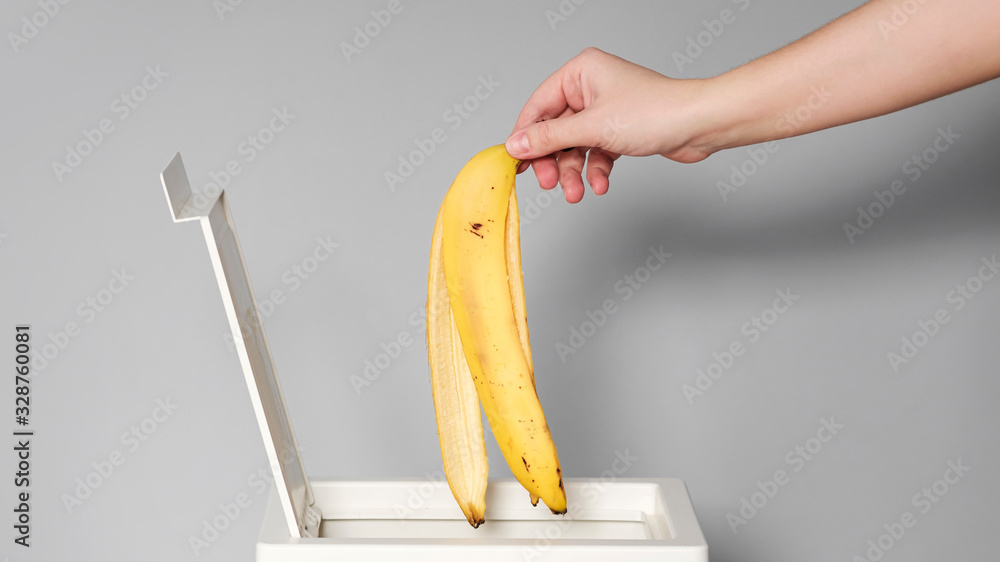 Hand puts banana peel in the bin for recycling. Activist taking care of ...