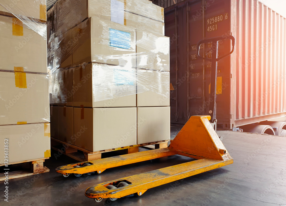 Hand pallet truck and stack of package boxes on pallet, truck container ...