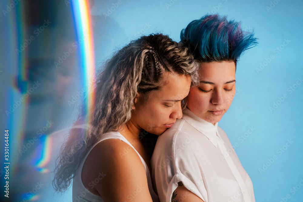 Real lesbian couple hugging with an iconic rainbow lgbt symbol. Prism ...