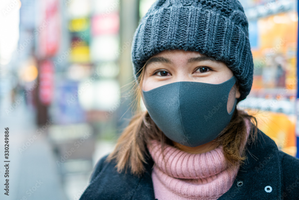 Asian young woman wearing a hygiene protective mask over her face while ...
