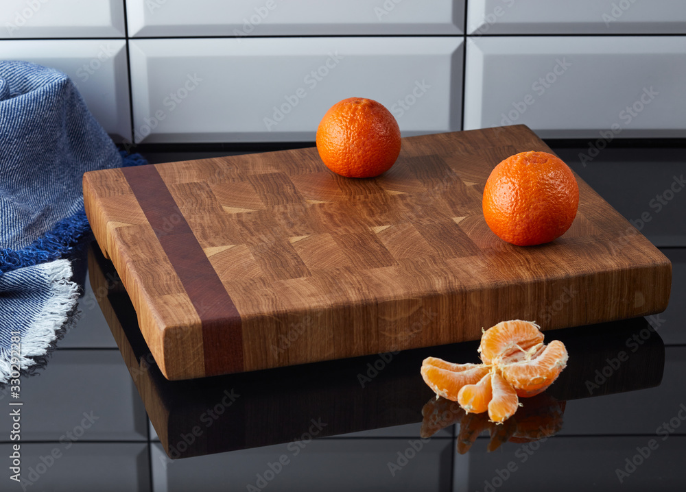 tangerines lay on a beautiful chopping Board, two whole and one peeled ...