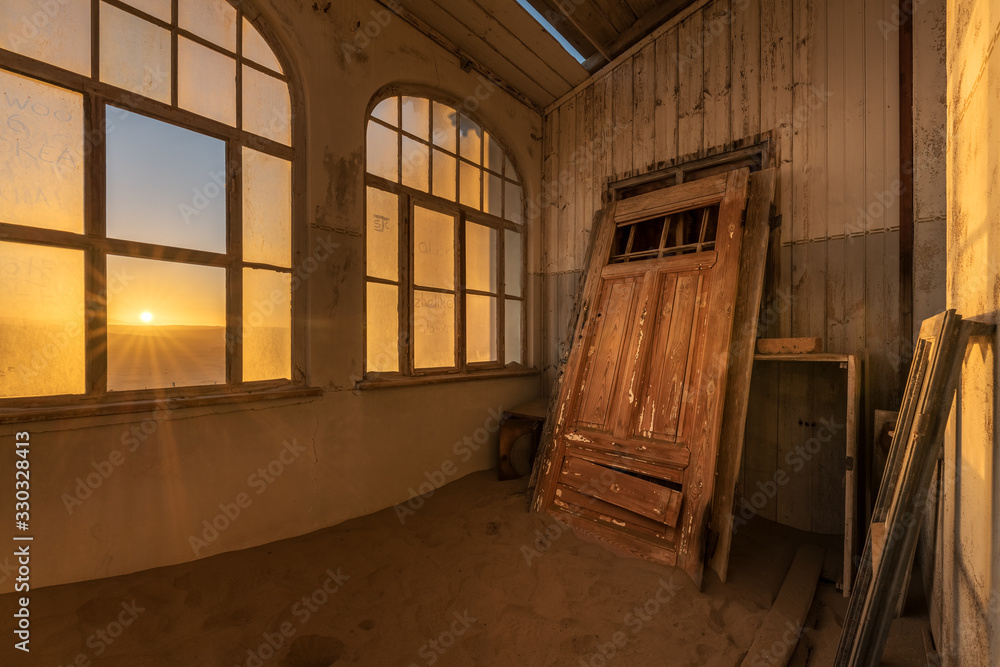 A dramatic photograph inside an abandoned house at sunrise, with a ...