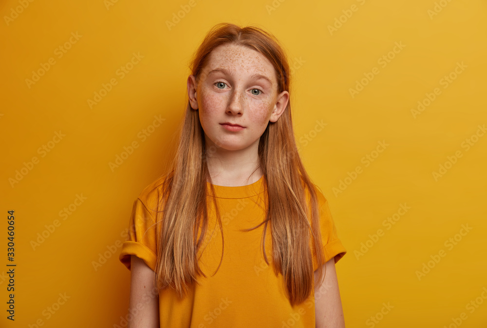 Indoor shot of good looking ginger girl tilts head, has charming look ...