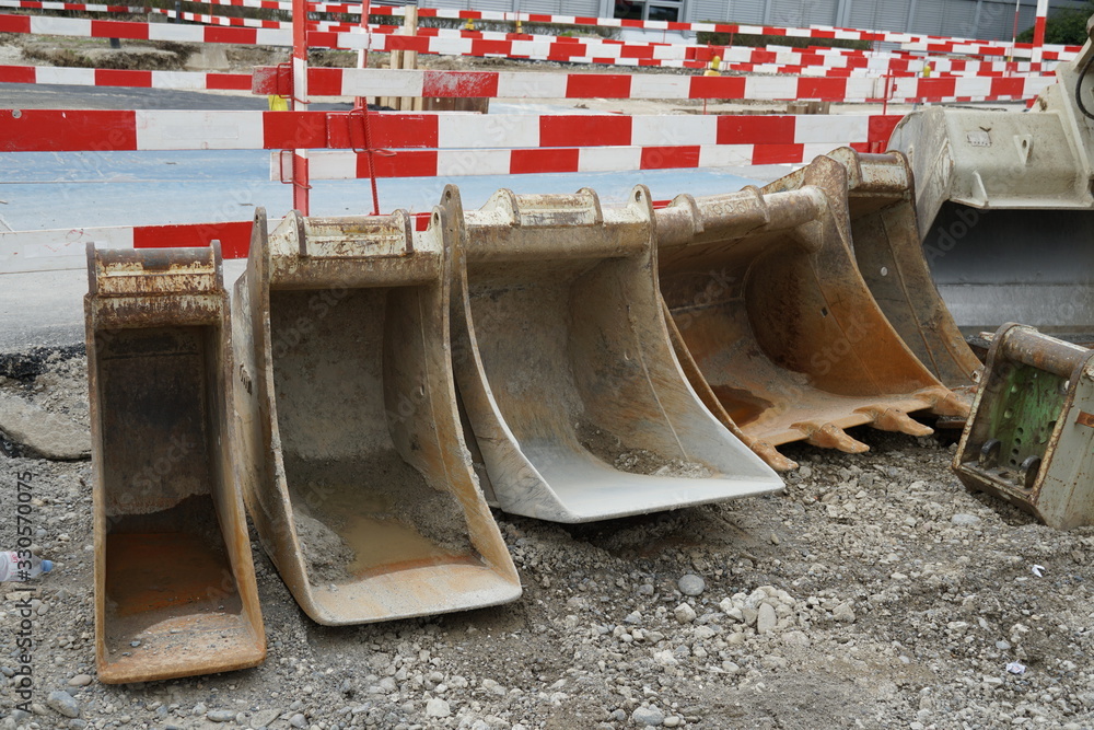 bulldozer dipper buckets of various size covered with rust, standing in ...