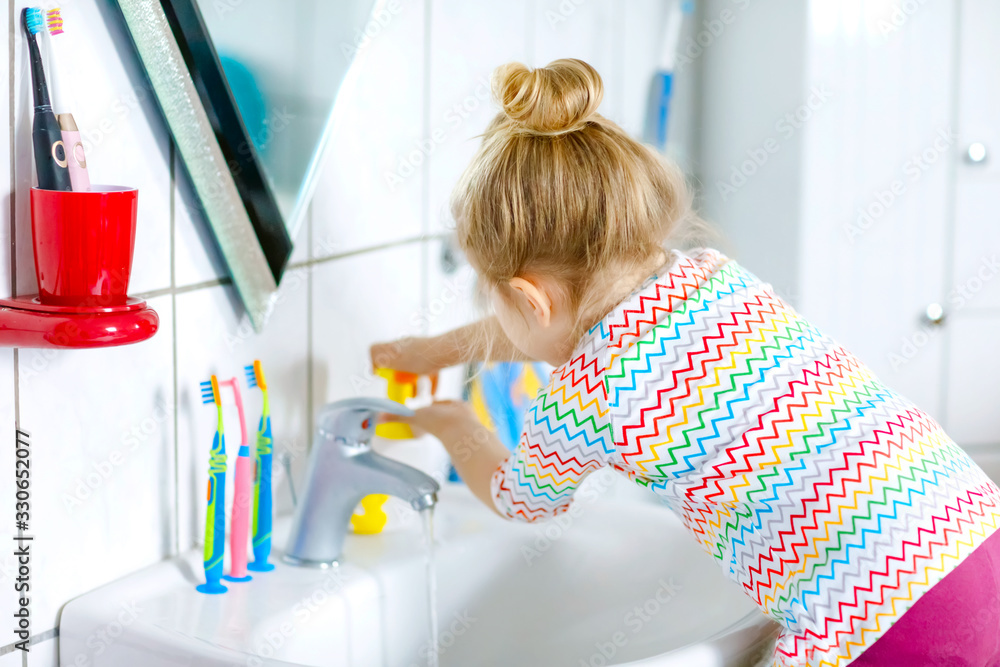 Cute little toddler girl washing hands with soap and water in bathroom ...