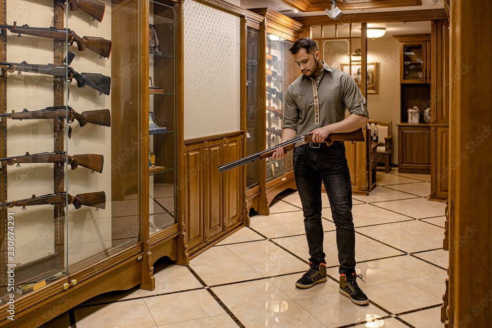 caucasian customer inspecting rifle in guns store, he liked this ...