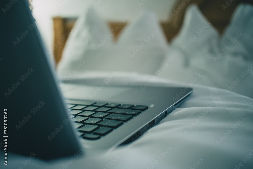 Detail view of a laptop keyboard sitting on a bed in hotel room ...