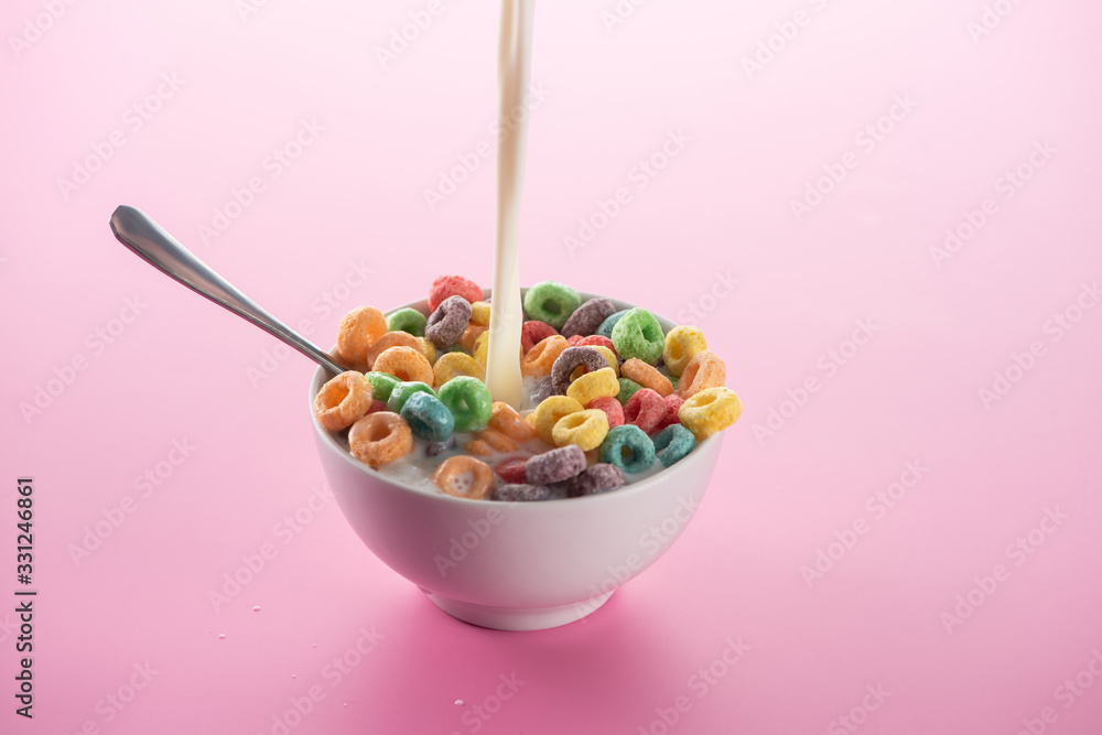 bright multicolored breakfast cereal in bowl with pouring milk and ...