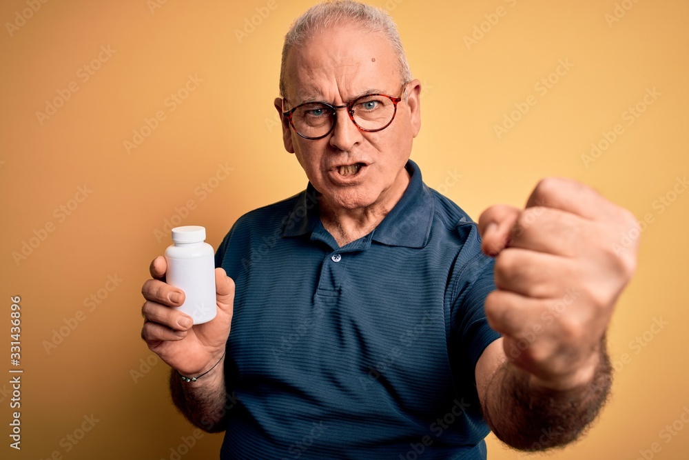 Middle age hoary man holding medicine pills standing over isolated ...
