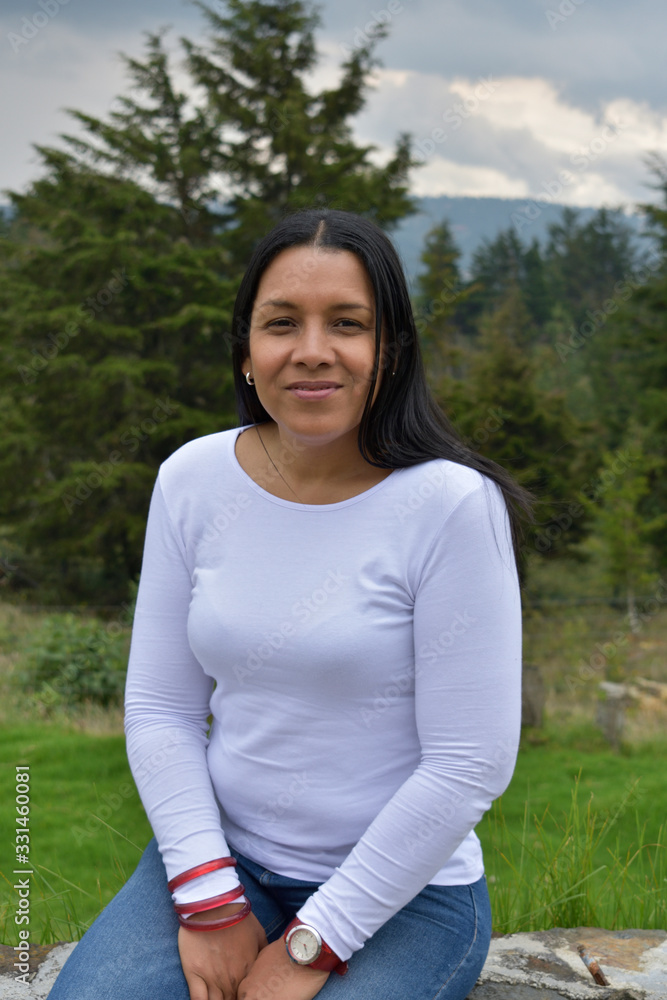 Foto de Stock Mujer madura morena latina bonita y sonriendo con una montaña de fondo | Adobe Stock