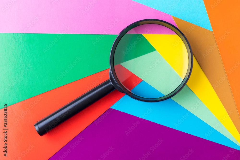 Magnifying glass on multi-colored sheets of paper. Search for diversity ...