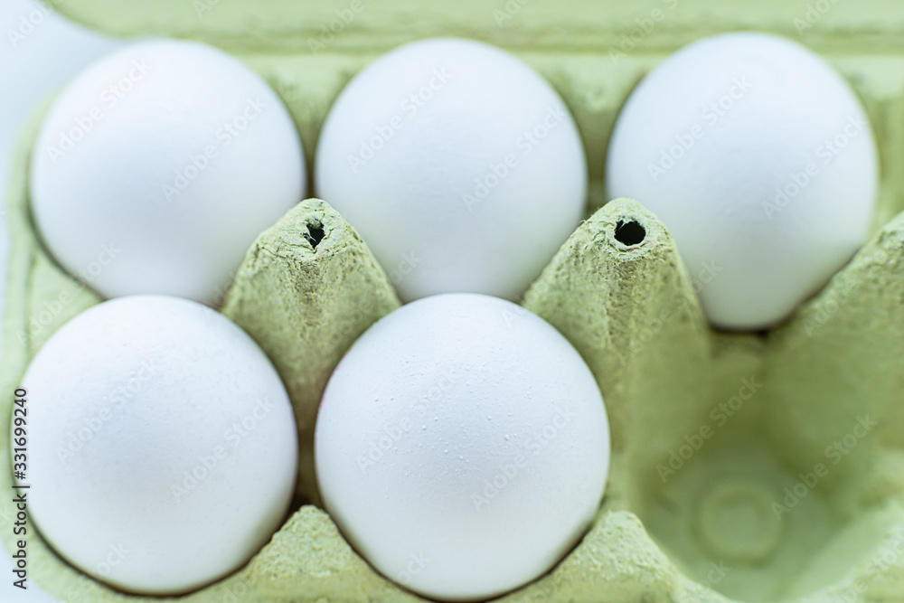 five white clean chicken eggs in a paper tray. next to one free ...