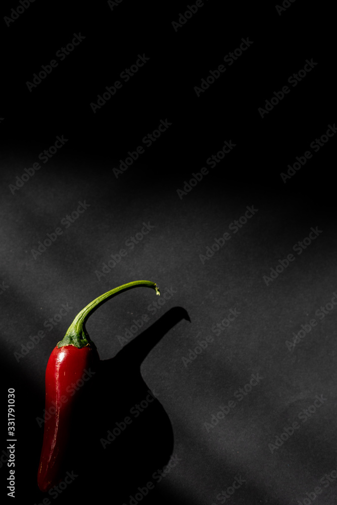 red hot chili pepper in shadow on black backdrop Stock Photo | Adobe Stock