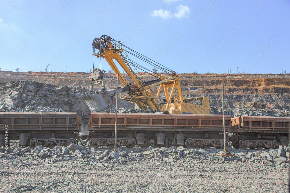 Excavator loading iron ore or granite into railway wagons Stock Photo | Adobe Stock