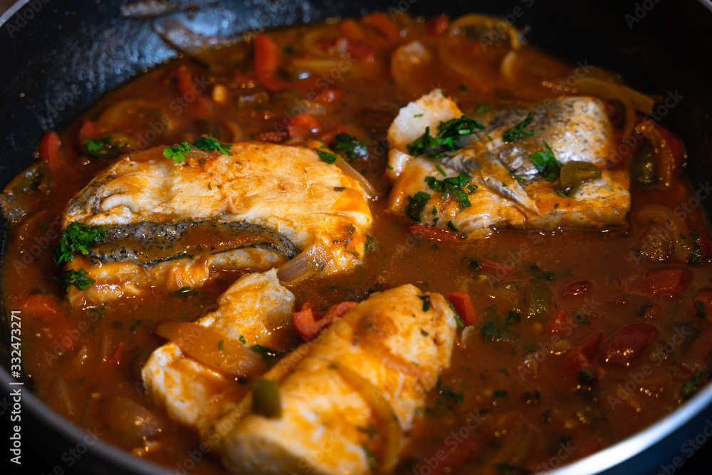 Hake fillet stew, cooking in a tomato sauce with red pepper sauce, with ...