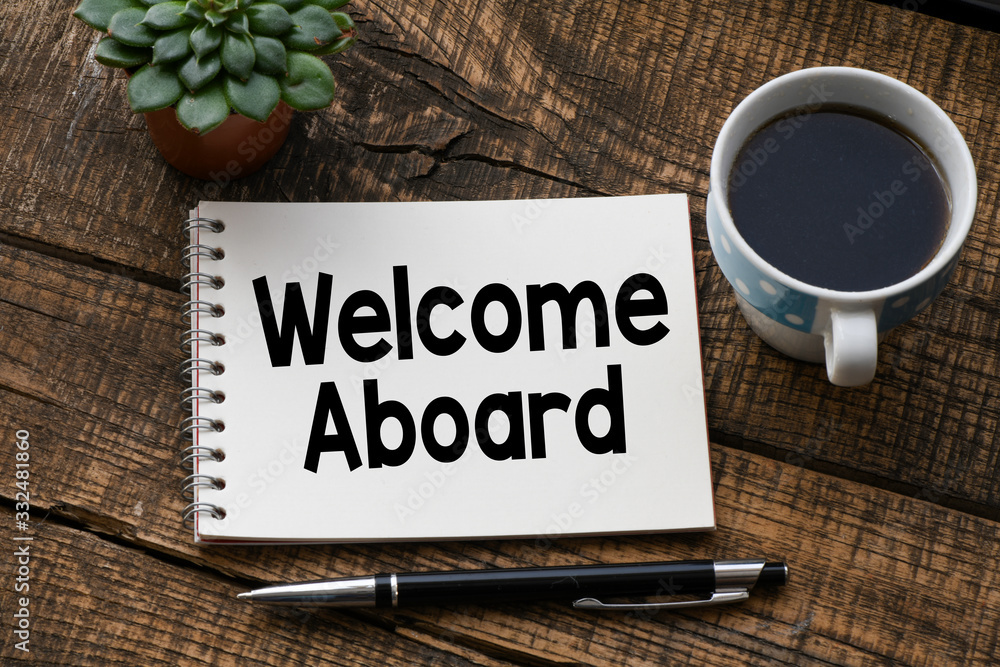WELCOME ABOARD text inscribed in the notebook on a wooden table. Stock ...