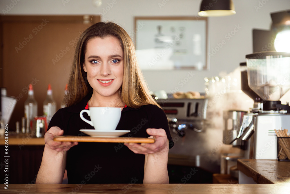 Beautiful female barista is working in coffee shop. Attractive woman is ...