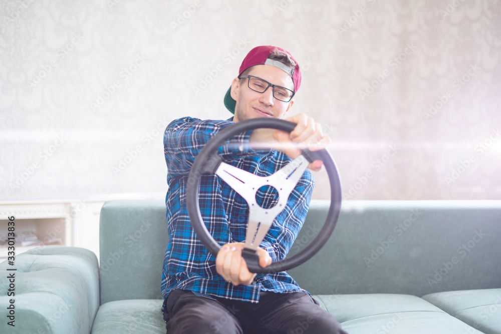 young man hold a steering wheel and imagine himself as a race driver ...