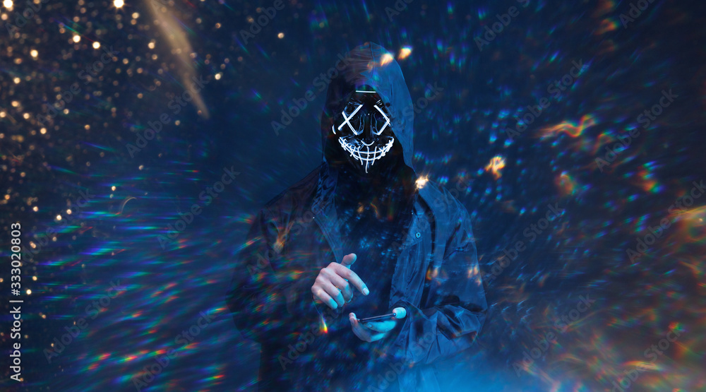 Dangerous hooded hacker with smartphone in his hand. Internet, cyber crime, cyber attack, system ...