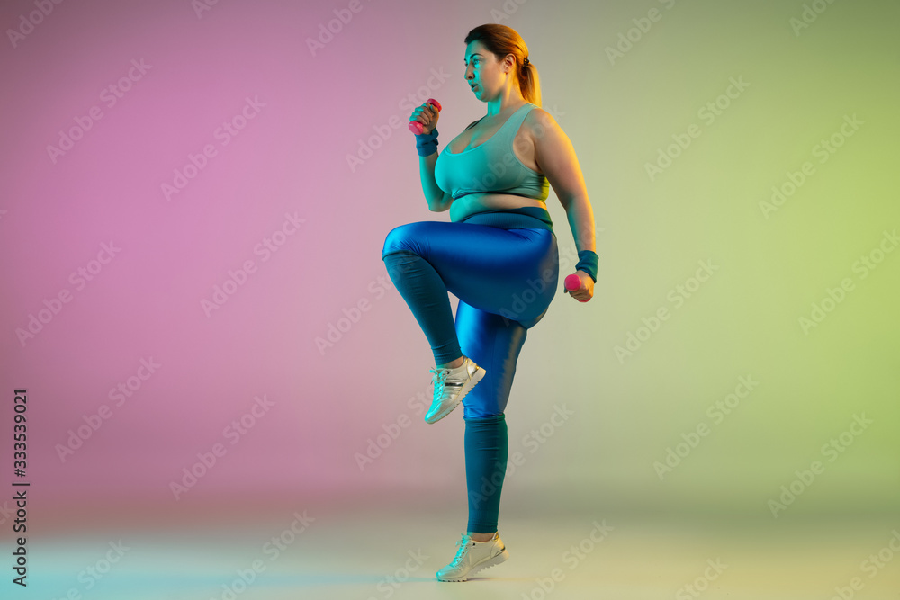 Young caucasian plus size female model's training on gradient purple ...