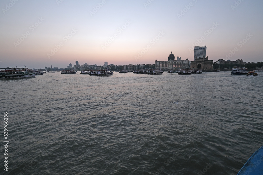 Taj Mahal hotel, Gateway of India and tourist boats in water of Arabian Sea on sunset in Mumbai ...