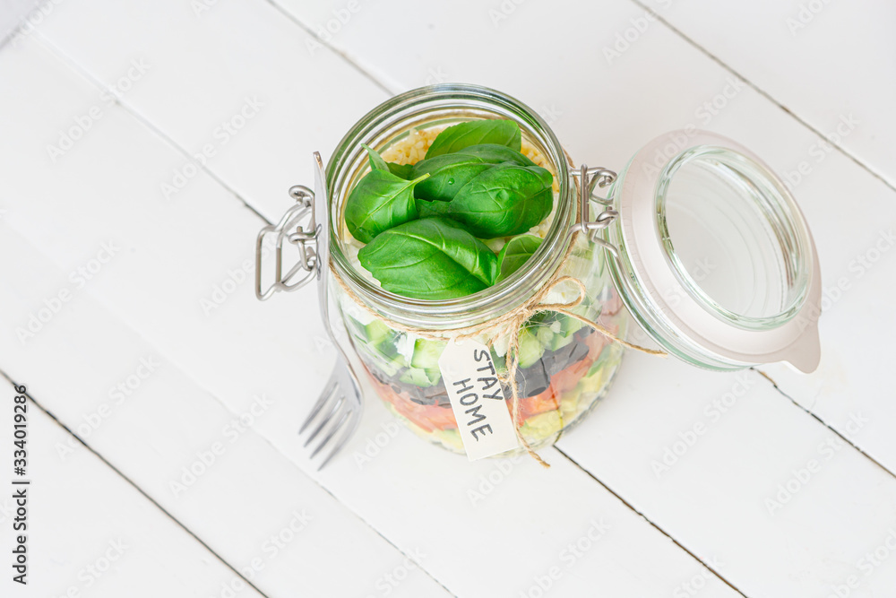 Vegetables salad in a jar with fork tied with a rope on white wooden ...