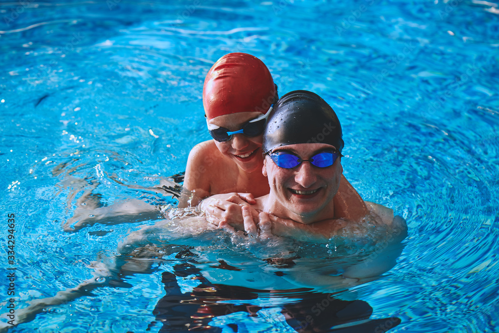 Dad and trainer teaches boy son to swim, have fun, play and splash in a ...