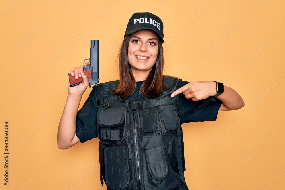 Young beautiful brunette policewoman wearing police uniform bulletproof ...