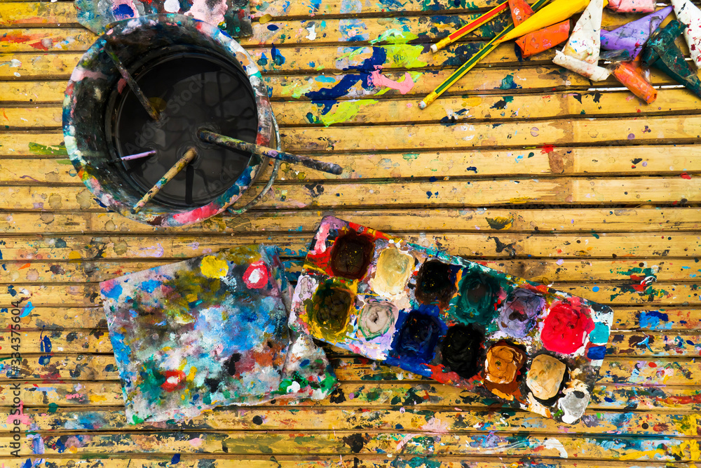 Various acrylic paint in palette color with paintbrush in water bucket ...