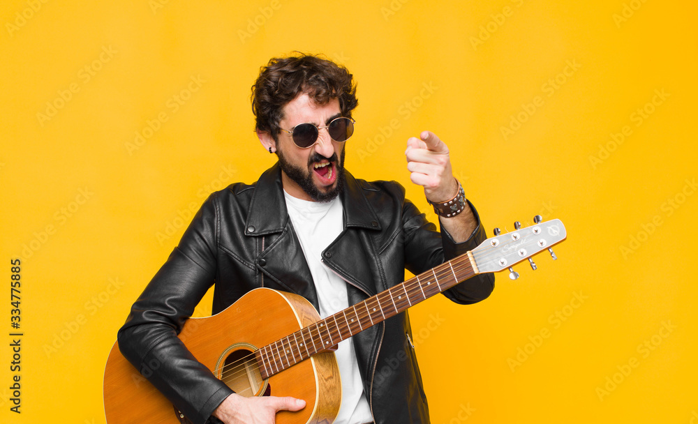 young musician man pointing at camera with an angry aggressive ...