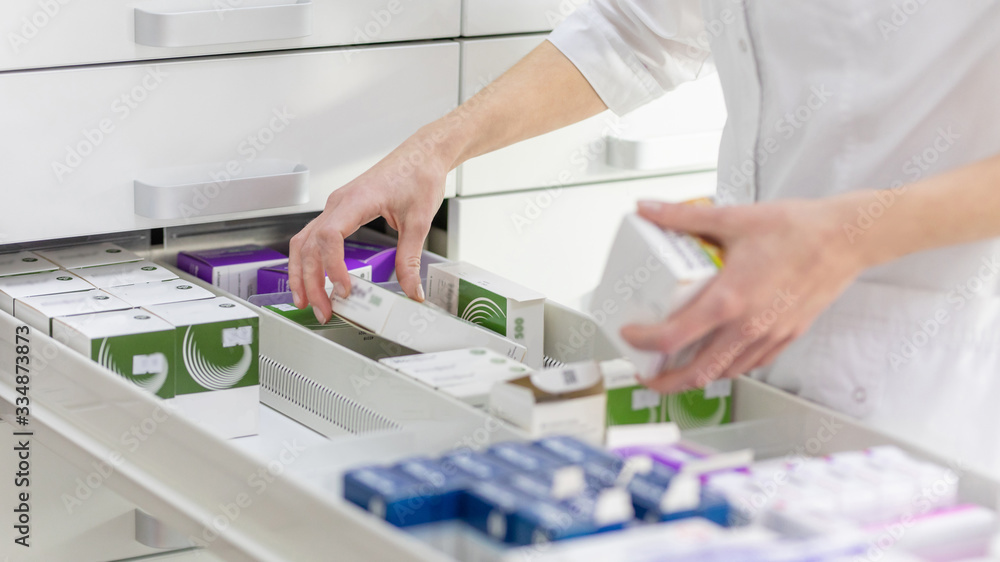 Pharmacist holding medicine box and capsule pack in pharmacy drugstore ...