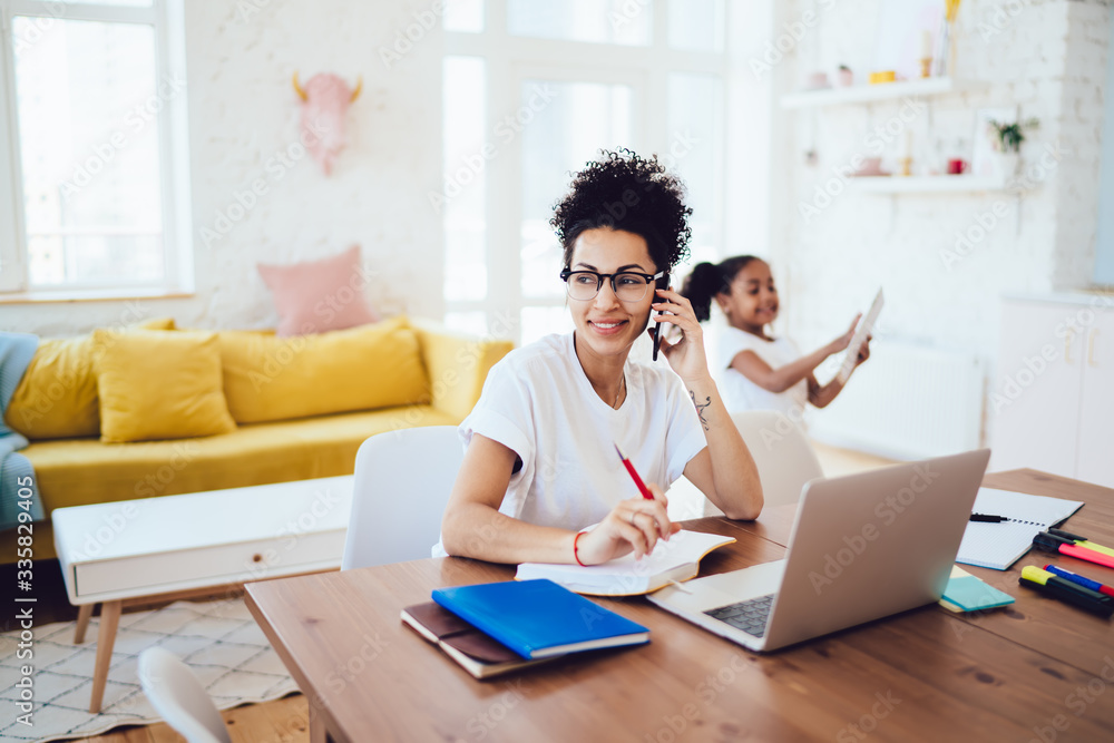 Cheerful black parent answering call near child Stock Photo | Adobe Stock