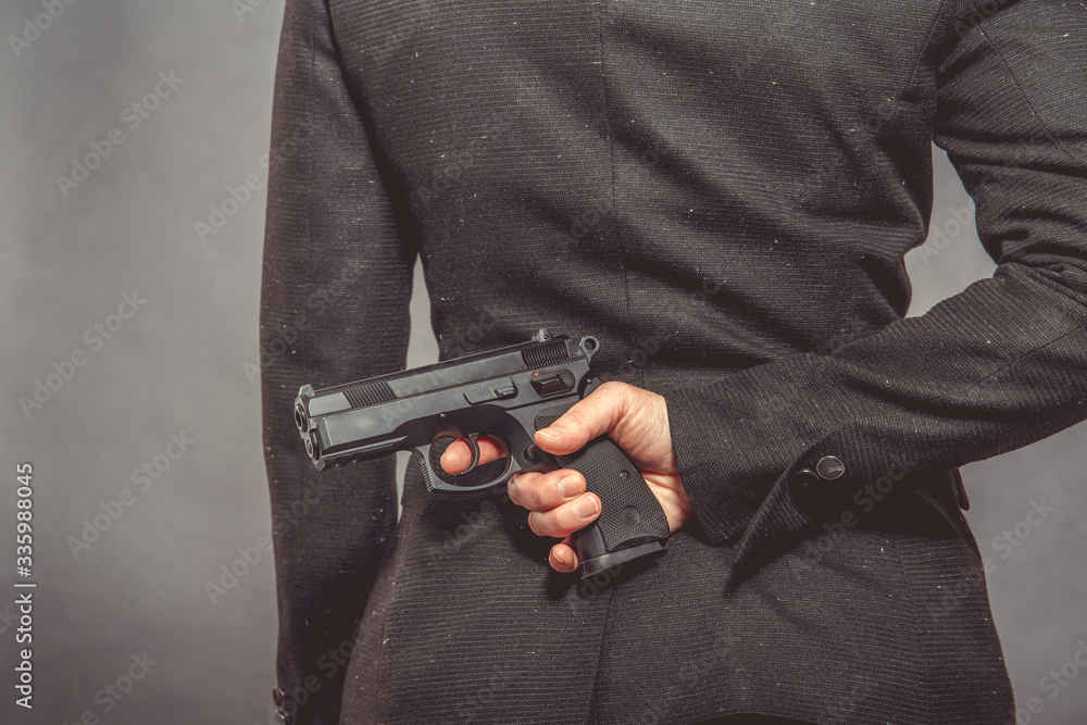 pistol in hand hidden behind agent's back. portrait of woman with gun ...