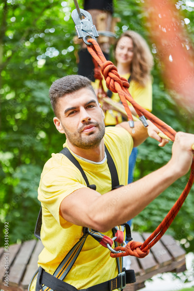 Man on bridge in climbing forest secured with rope Stock Photo | Adobe ...
