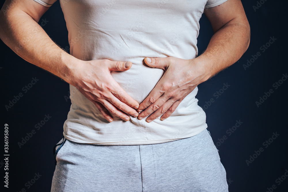 The guy is holding his hands to his stomach. The concept disorders of the stomach, severe pain ...