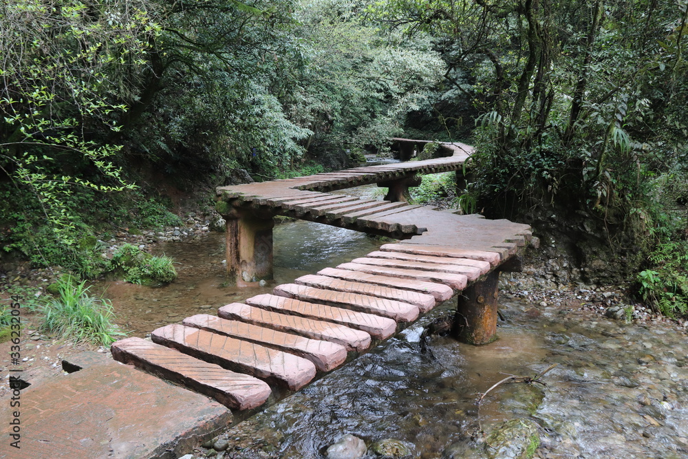 wooden bridge pathway a river in a mountain forest in Sichuan, China ...
