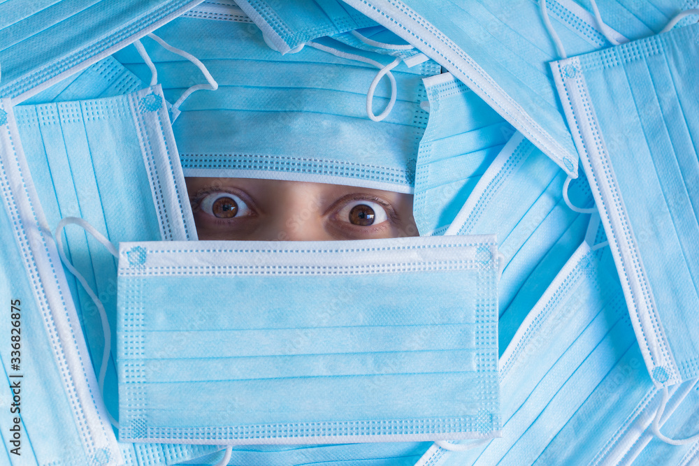 Frightened woman face covered with a bunch of disposable surgical masks ...