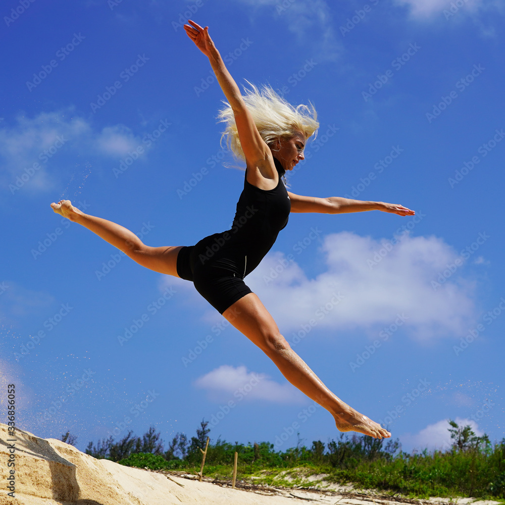 beautiful blonde girl dancer jumping on the white sand. gymnast doing ...