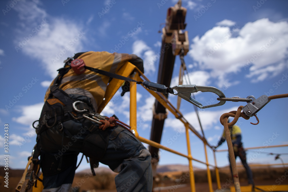 Safe workplace rigger wearing working at heights harness clipping an ...