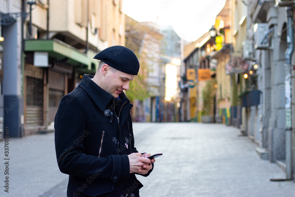 Stylish young man standing alone on empty city streets during lockdown ...