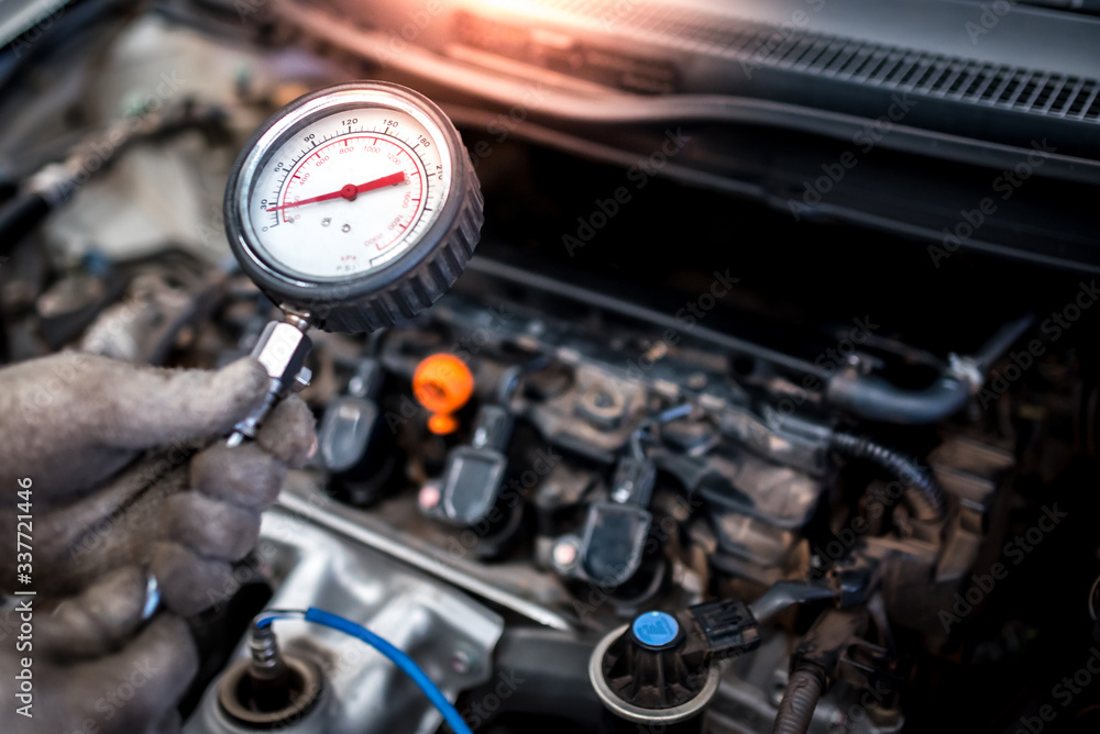 The auto mechanic is about to measure compression in the cylinder of a ...