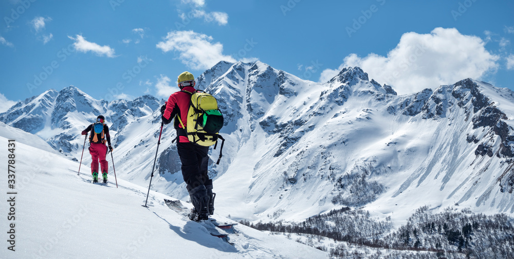 Two active men ski touring on mountain skis and splitboard at sunny ...