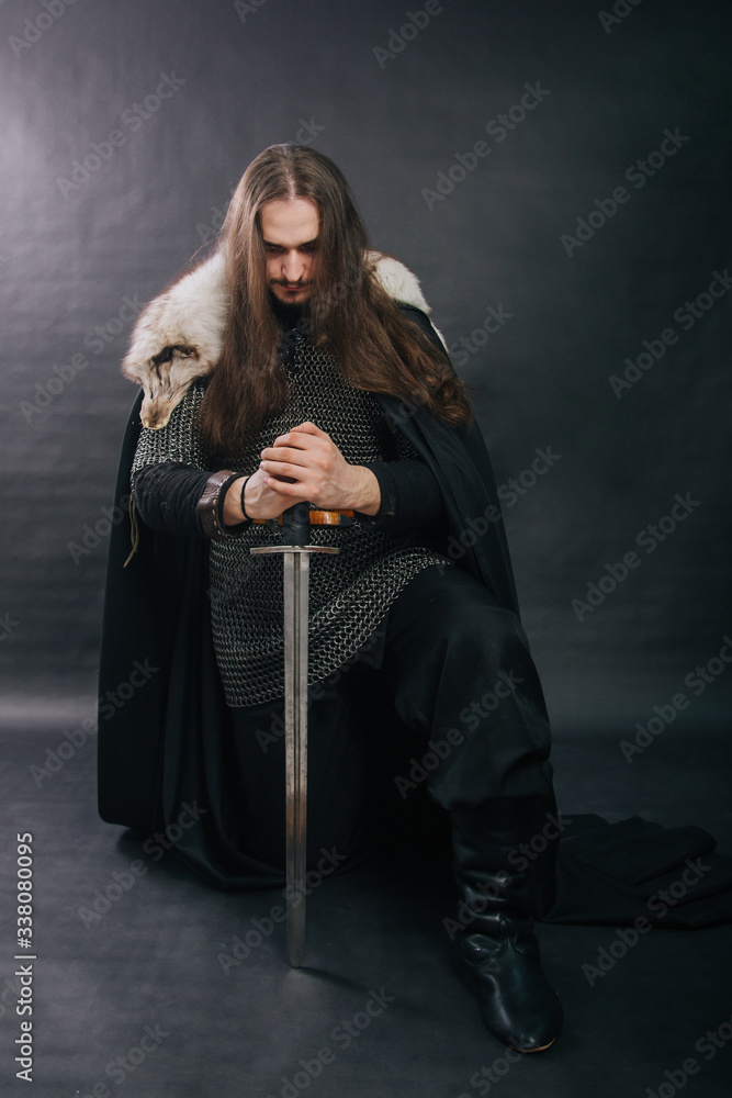 Warrior in chain mail and with a sword in a black cloak. Handsome guy ...